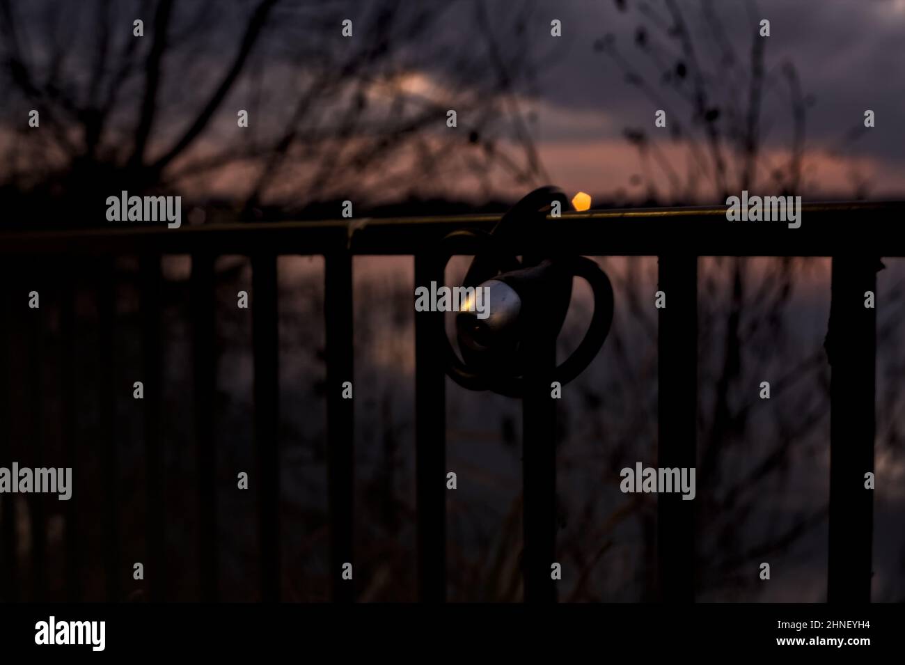 Padlock wrapped on a railing with the sky at twilight as background ...