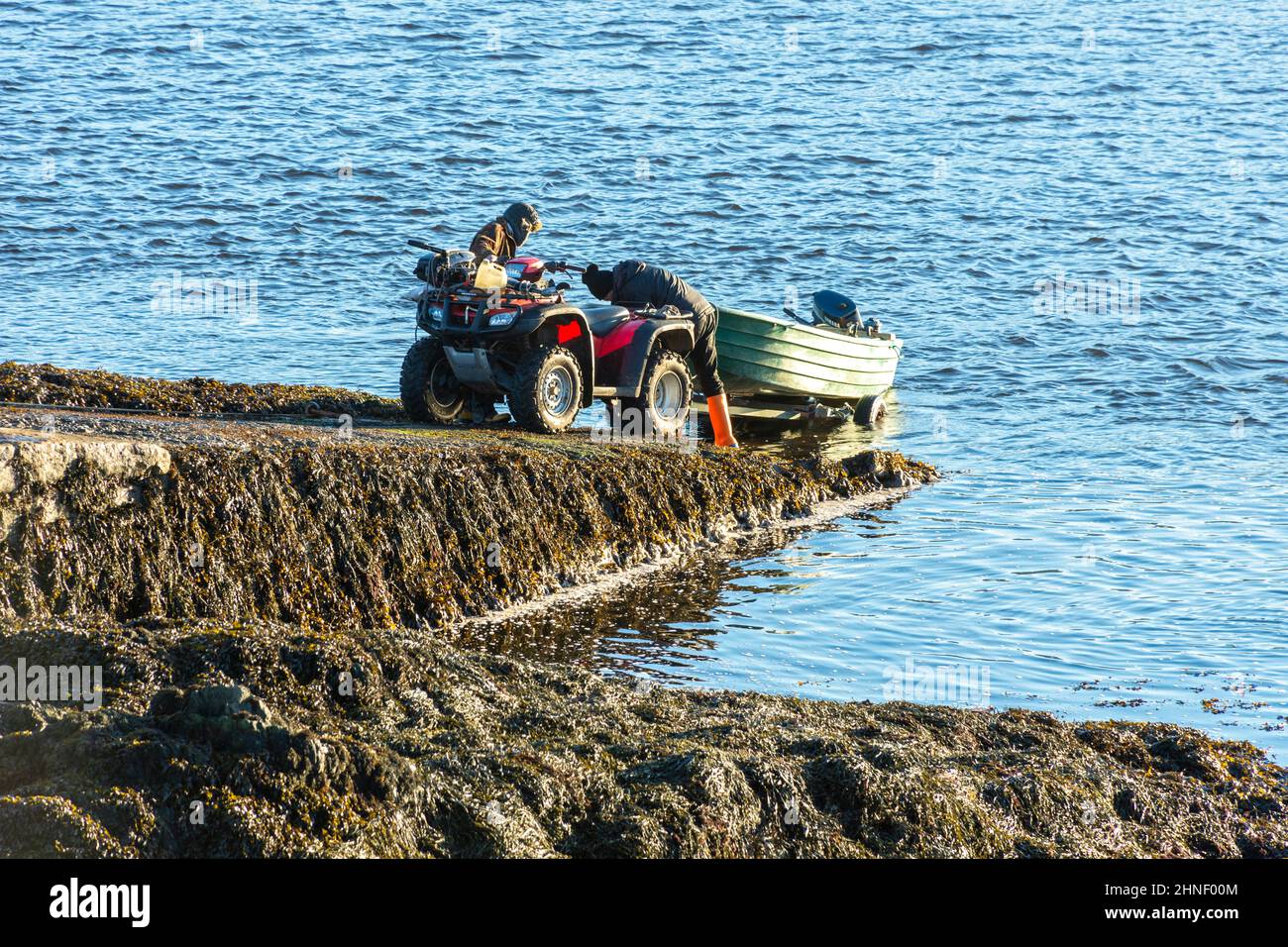 Two men launching a boat from a trailer on the jetty at Keoldale, on ...