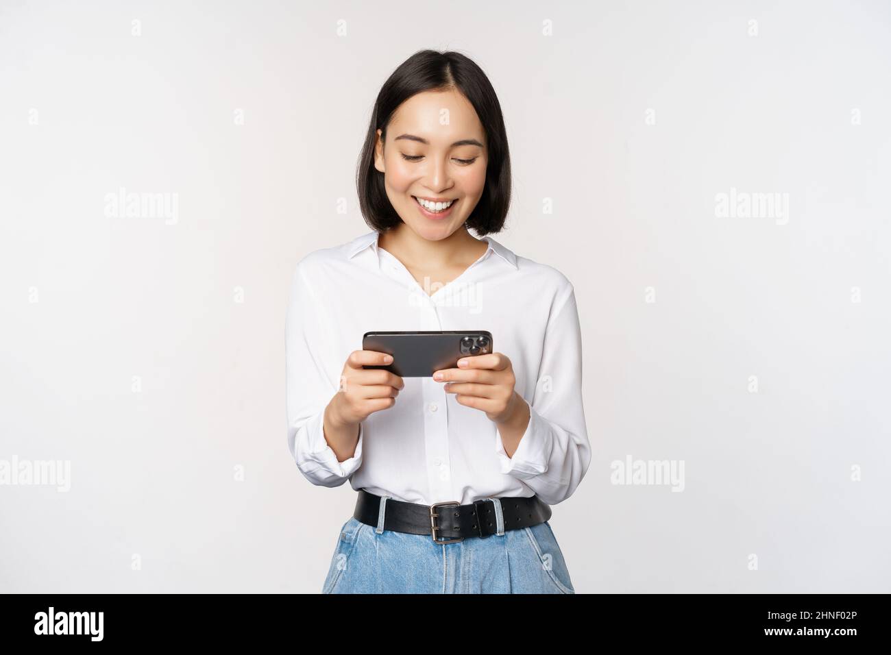 Young korean woman, asian girl playing mobile video game on smartphone ...