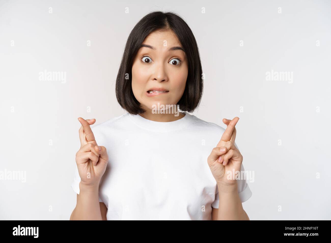 Hopeful asian girl cross fingers, making wish, anticipating, wishing ...