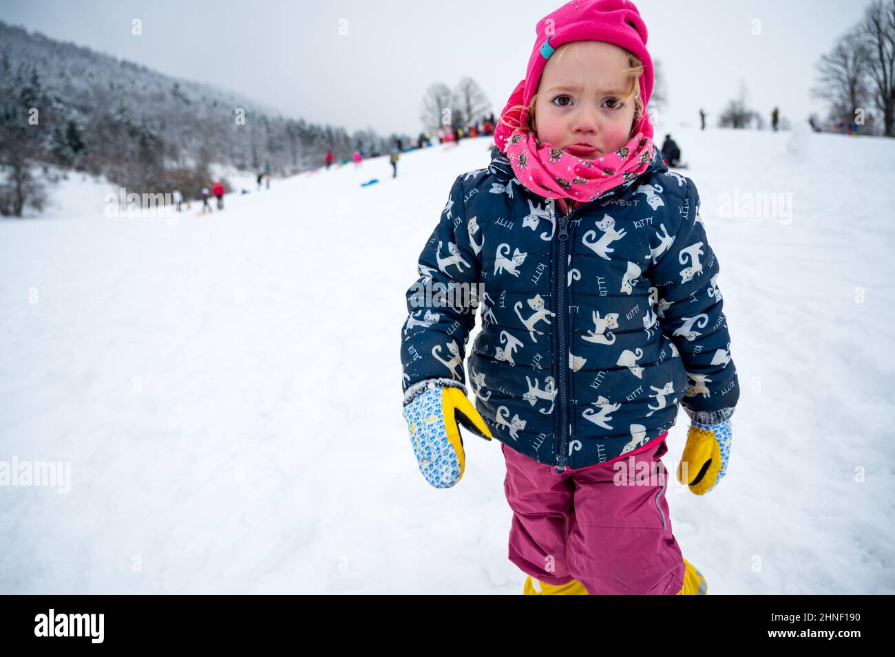 Sad girl wearing pink hat at snowy slope Stock Photo - Alamy