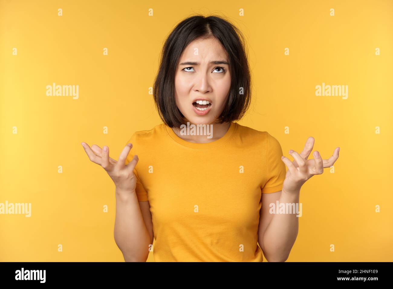 Image of angry asian woman, shouting and cursing, looking outraged ...