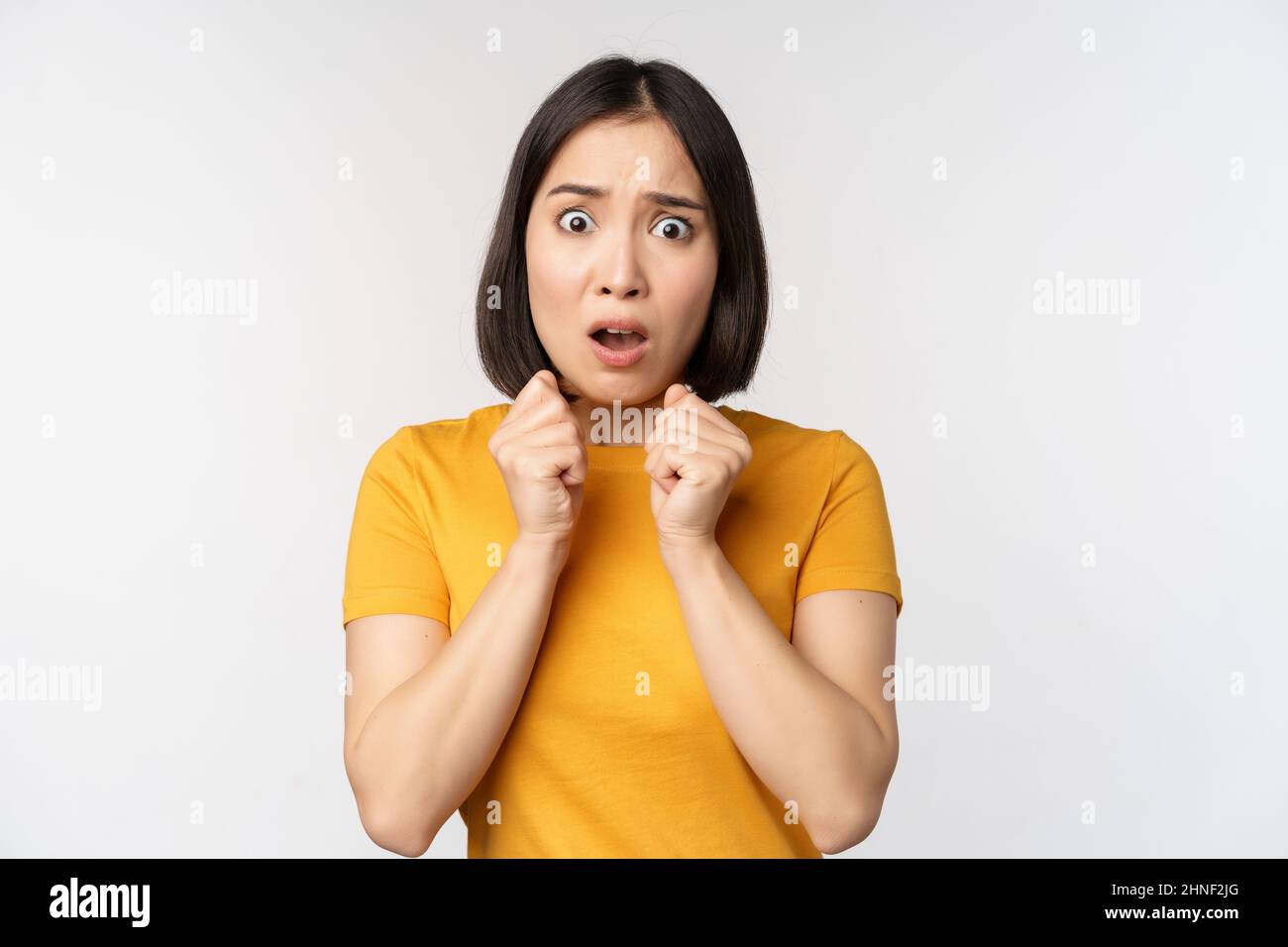 Portrait of scared asian woman shaking from fear, looking terrified and concerned, standing ...