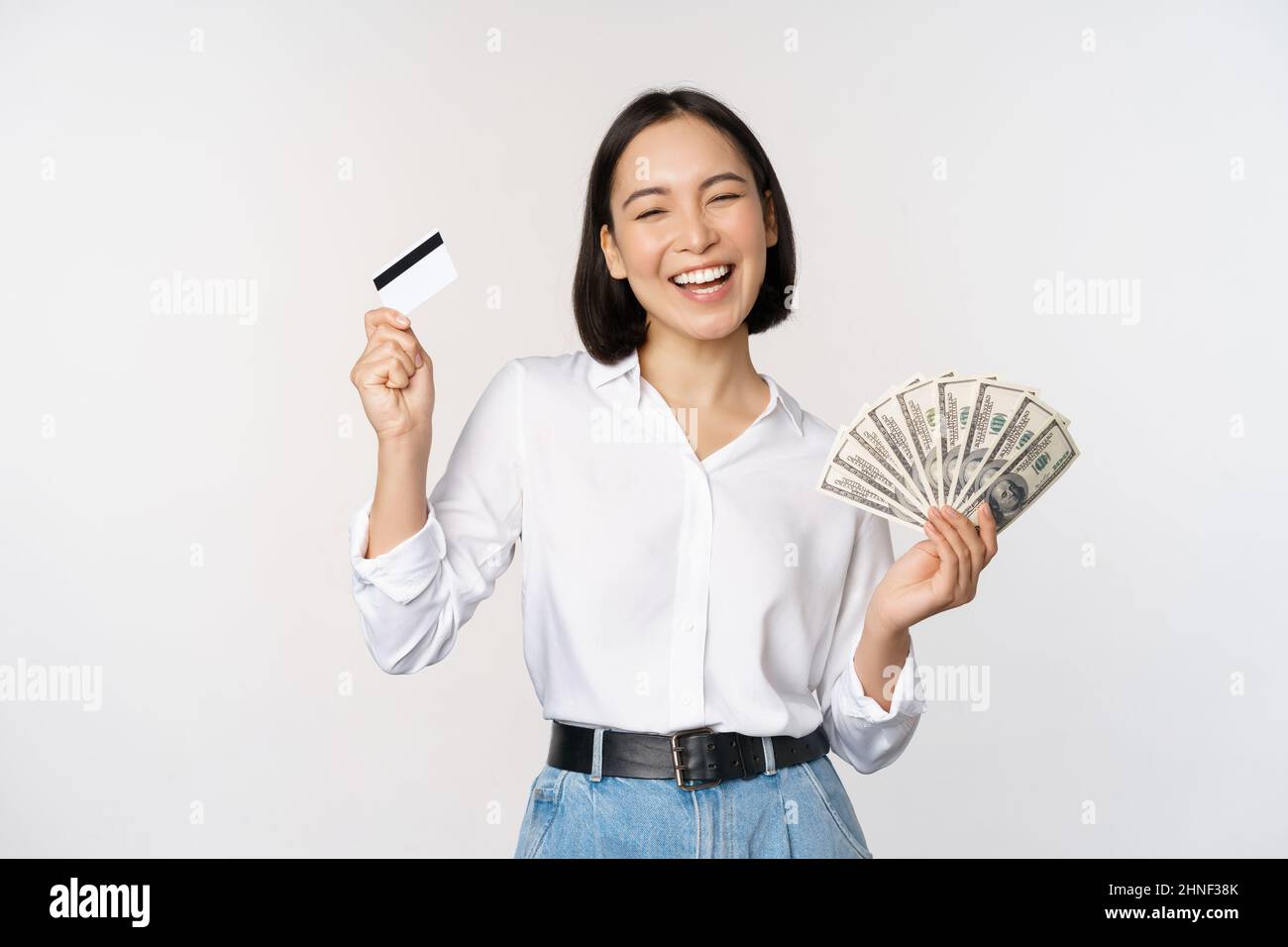 Happy korean woman holding credit card and money dollars, smiling and ...