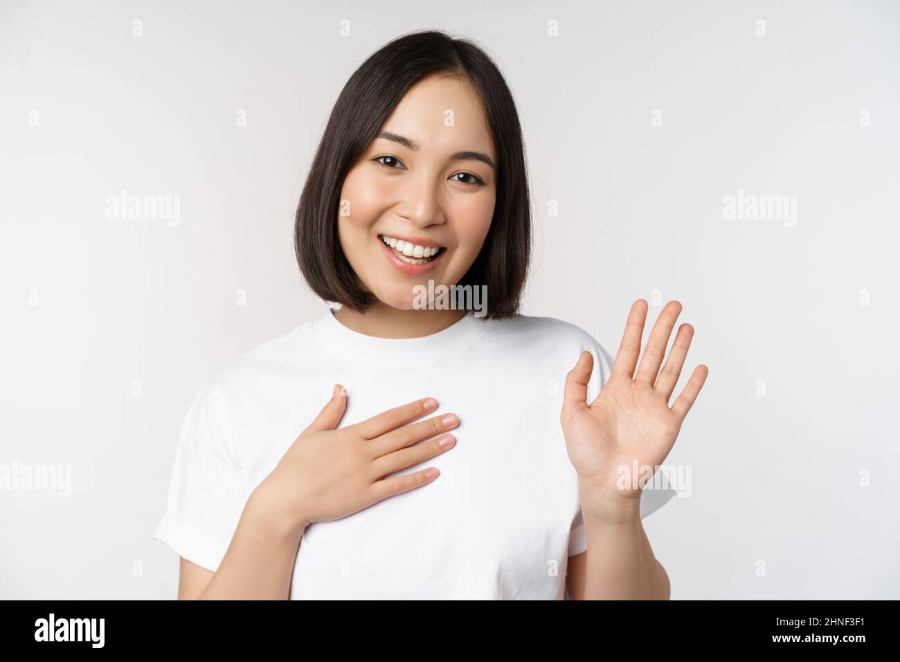 Portrait of beautiful korean girl raising hand, introduce herself, put ...