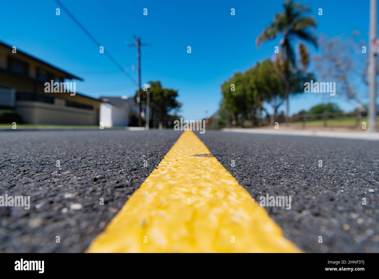 Yellow line road marking on asphalt road along blurry residential ...
