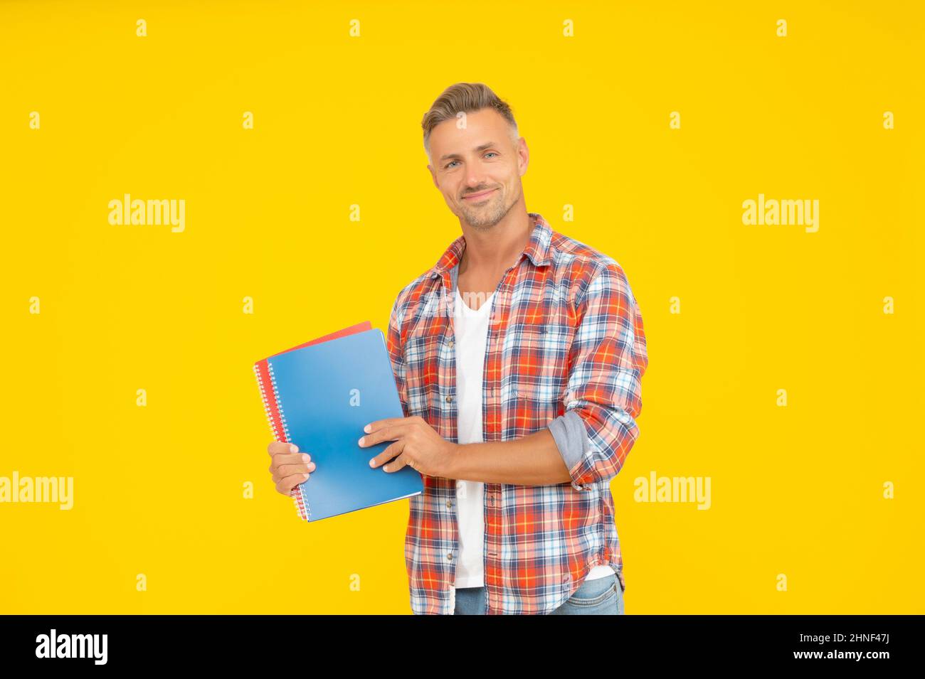 Happy university student holding books for education yellow background ...