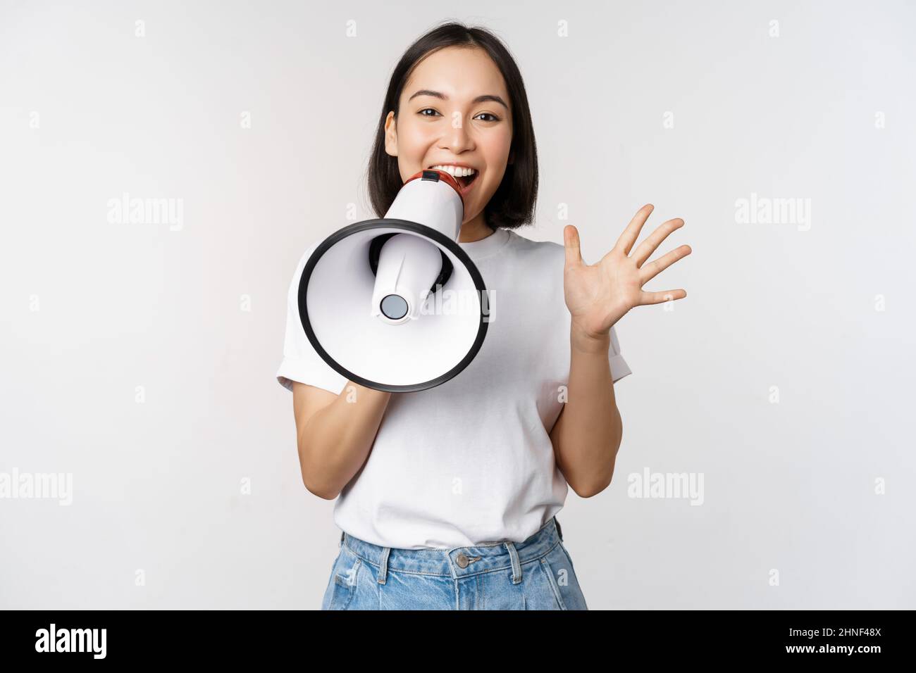 Happy asian woman shouting at megaphone, making announcement ...