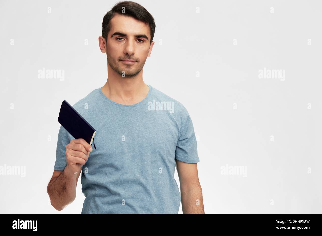 portrait man with a notepad in hand casual wear posing emotions light ...