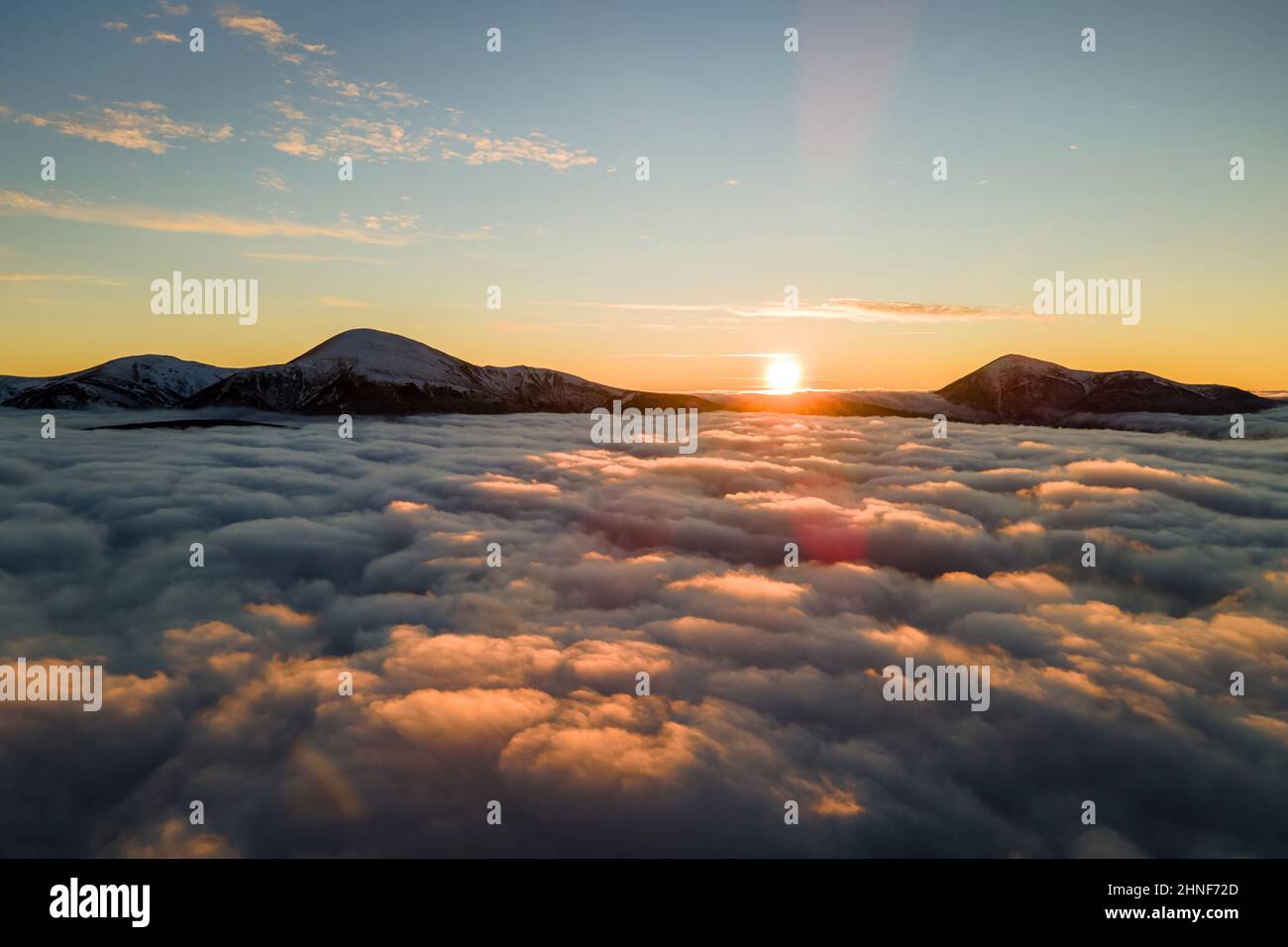 Aerial view of vibrant sunrise over white dense clouds with distant ...