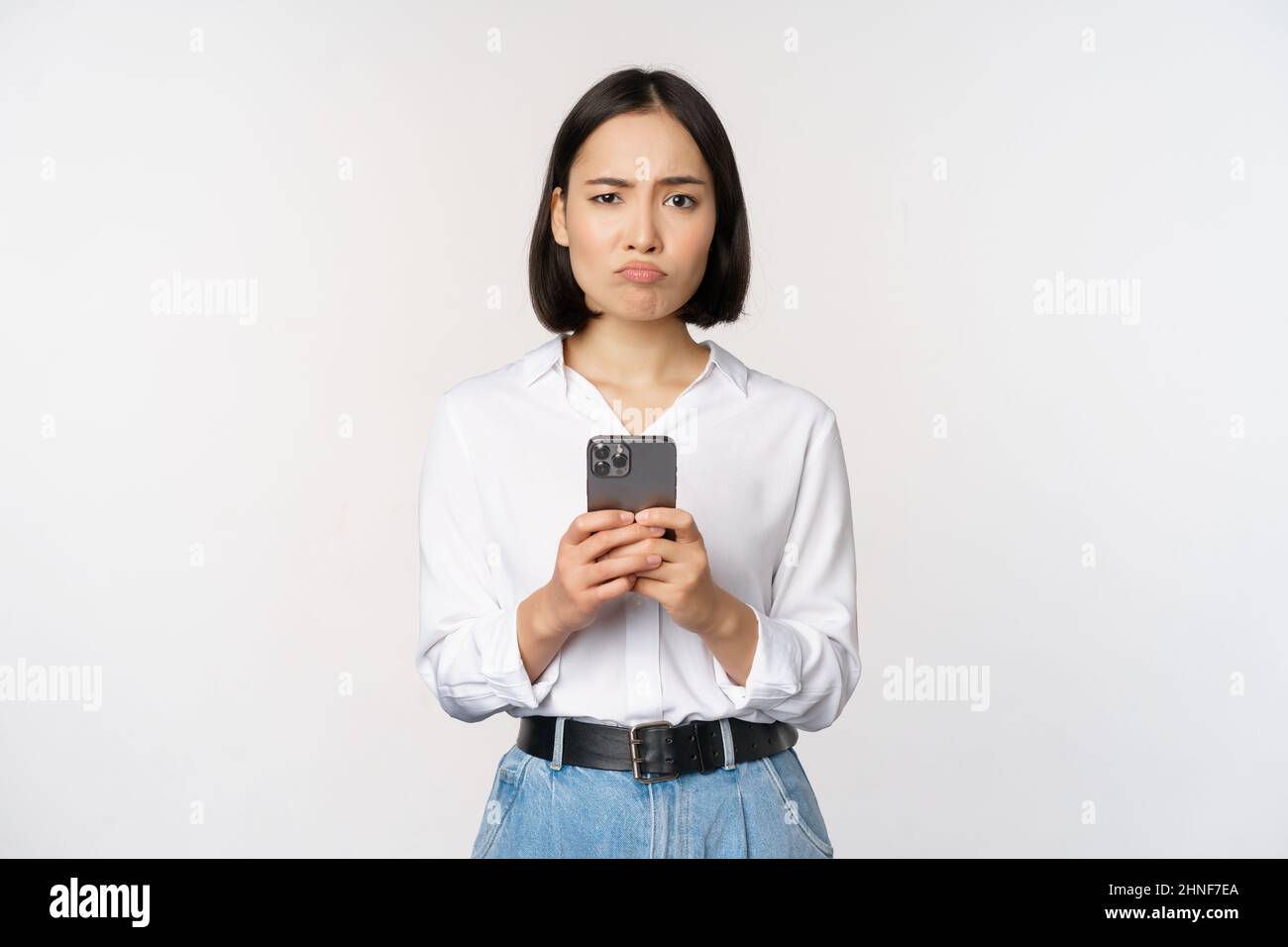 Asian woman holding smartphone and looking with doubt, disappointed ...