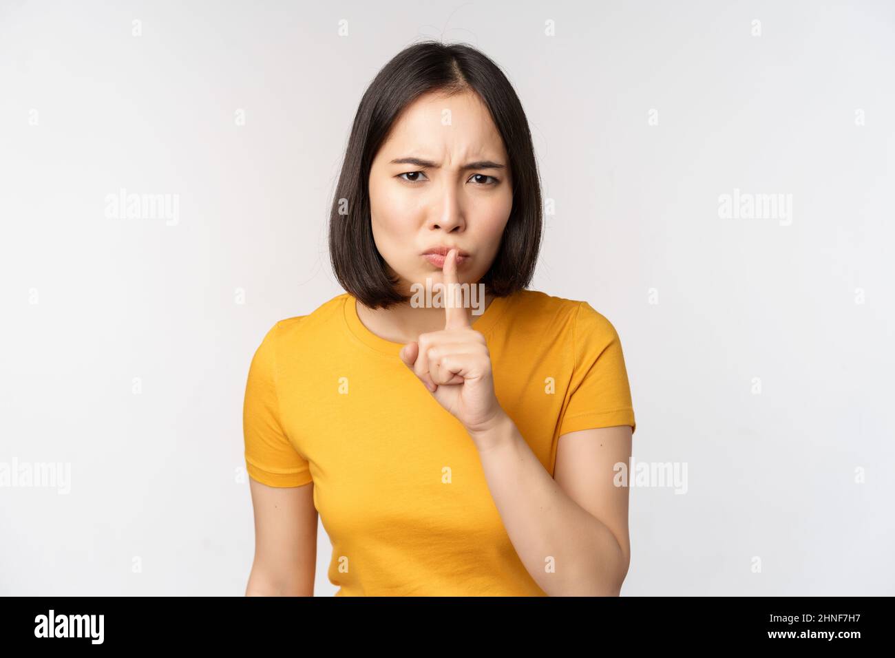 Portrait of angry asian woman shushing, press finger to lips, taboo ...