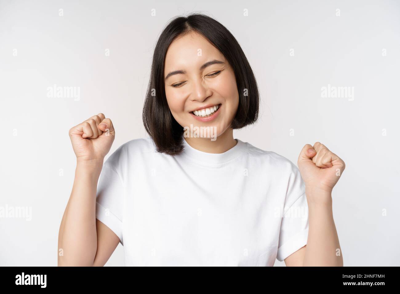 Dancing asian girl celebrating, feeling happy and upbeat, smiling ...
