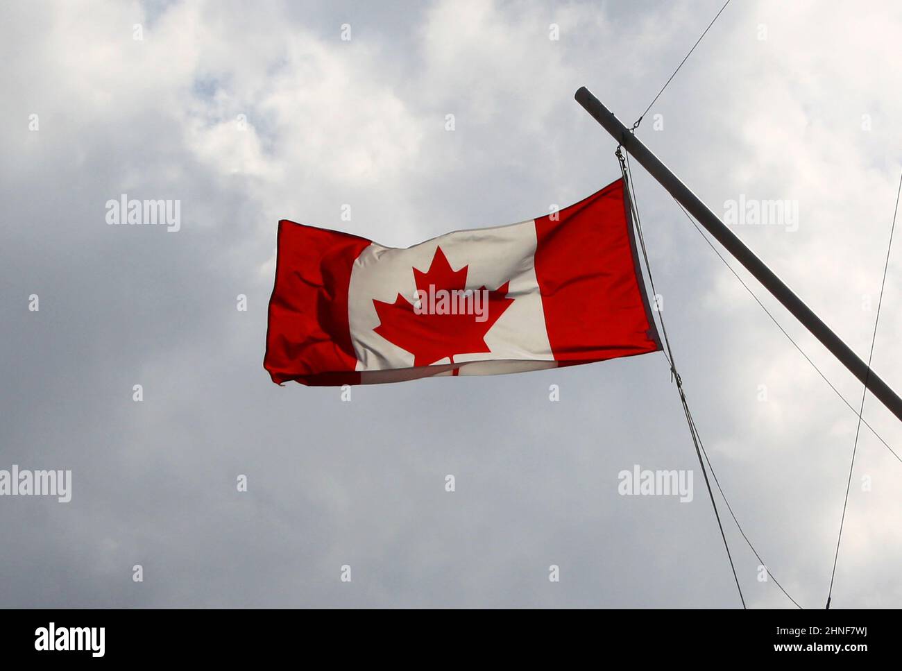 Low angle of the Canadian flag hanging on strings under a cloudy sky ...