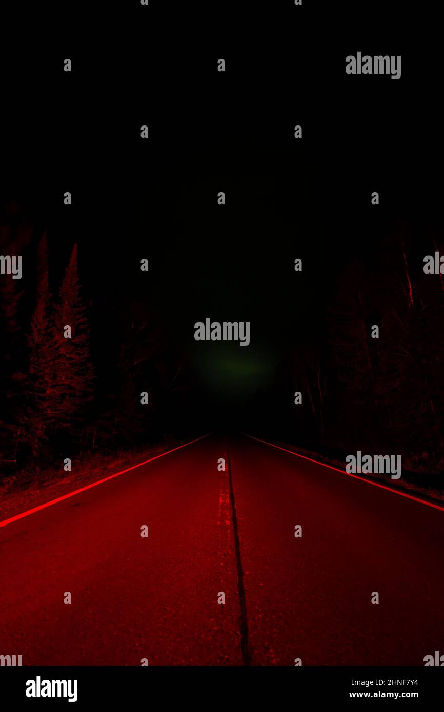 faint glow of the northern lights over a brake light glow on a road ...