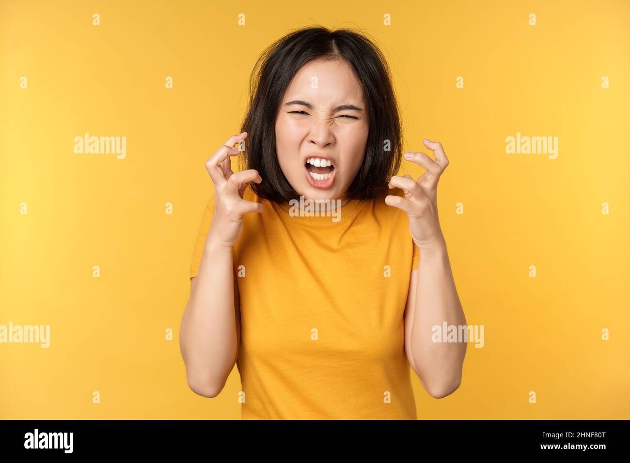 Image of angry asian woman, shouting and cursing, looking outraged ...