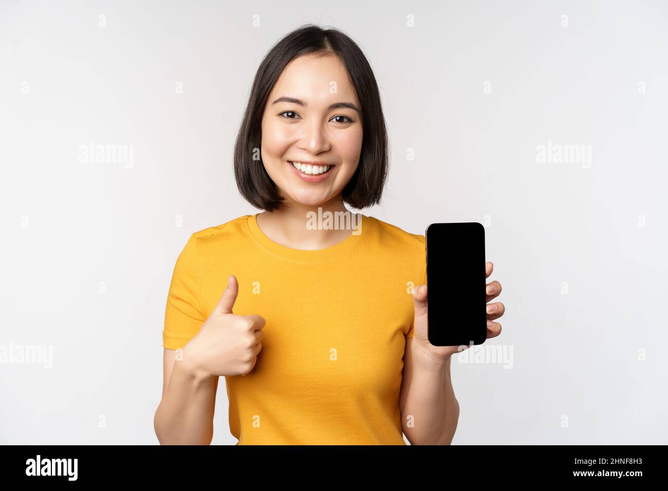 Technology and people concept. Smiling young woman showing thumb up and ...