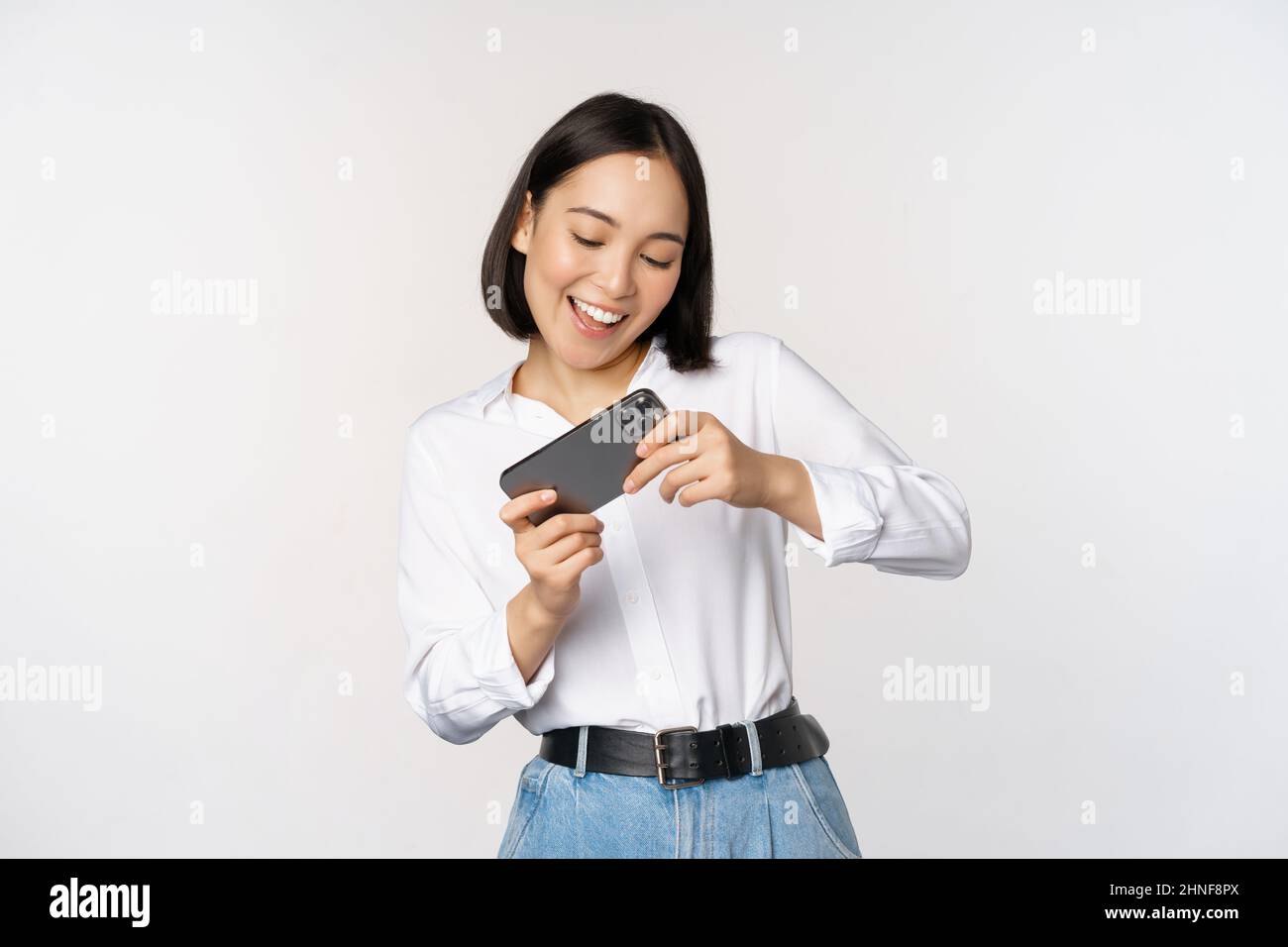 Young korean woman, asian girl playing mobile video game on smartphone ...