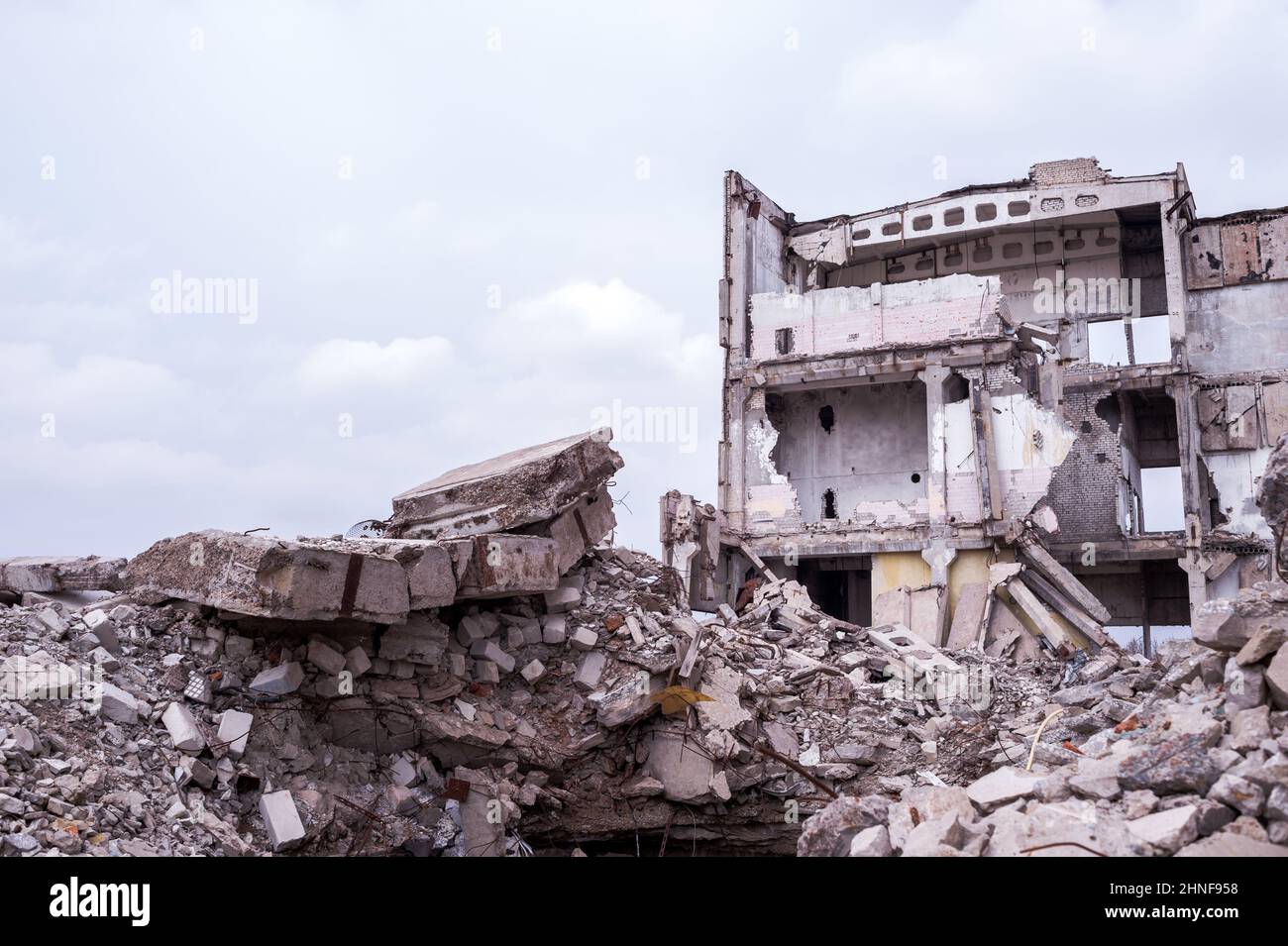 A ruined building against a gray sky with a pile of concrete rubble in ...