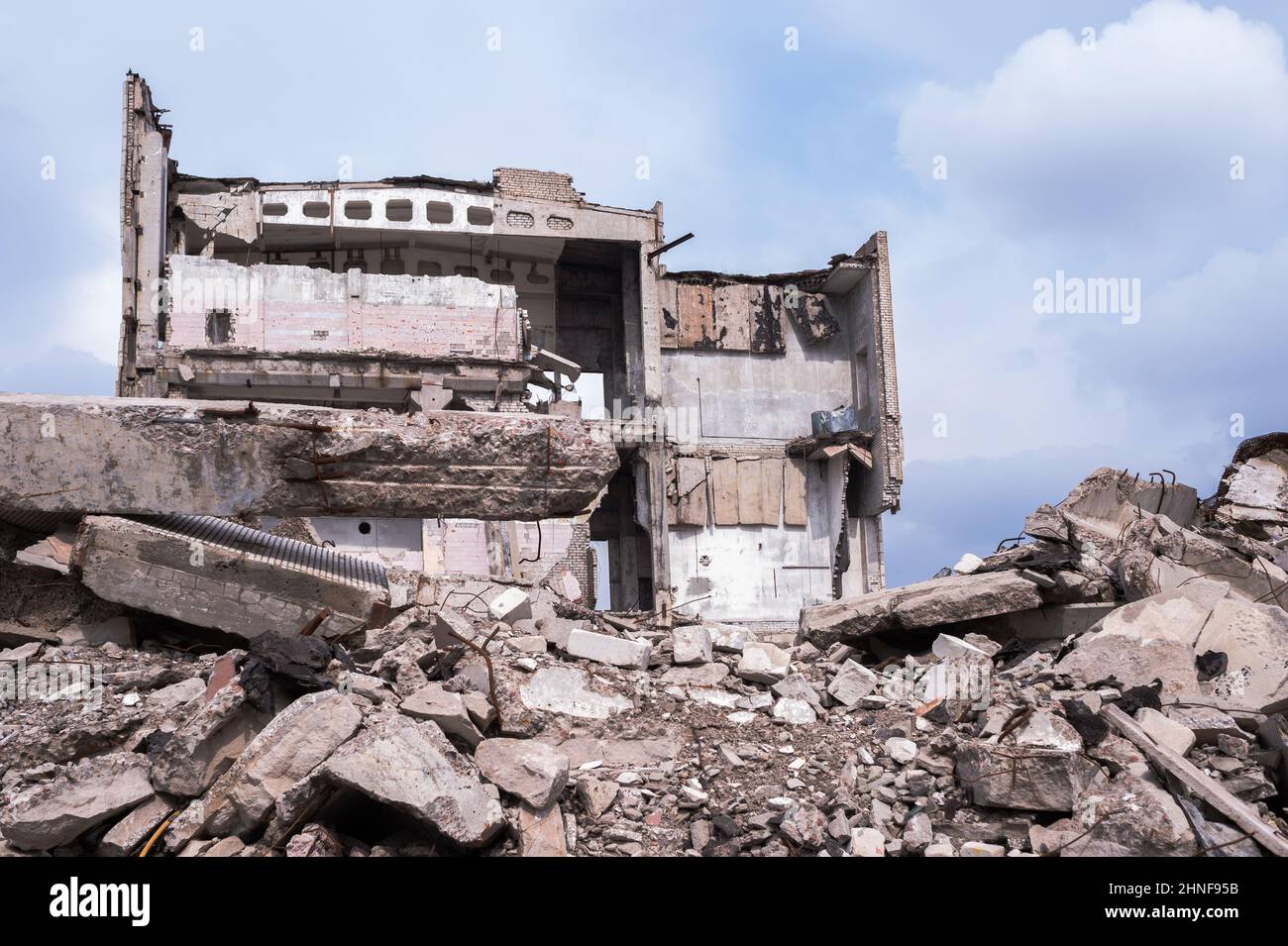 A ruined building against a blue sky with gray clouds with a pile of ...