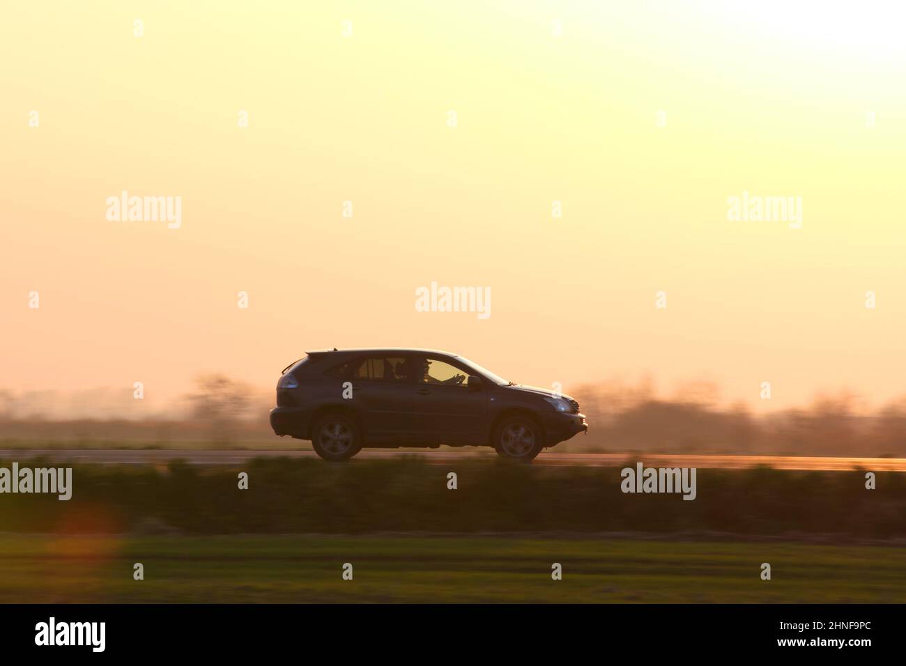 SUV car driving fast on intercity road at sunset. Highway traffic in ...