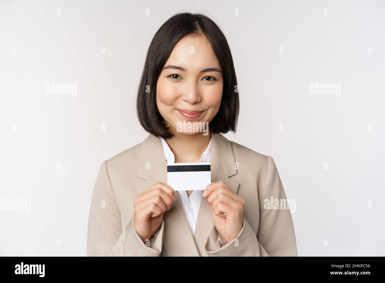 Smiling office clerk, asian corporate woman showing credit card ...
