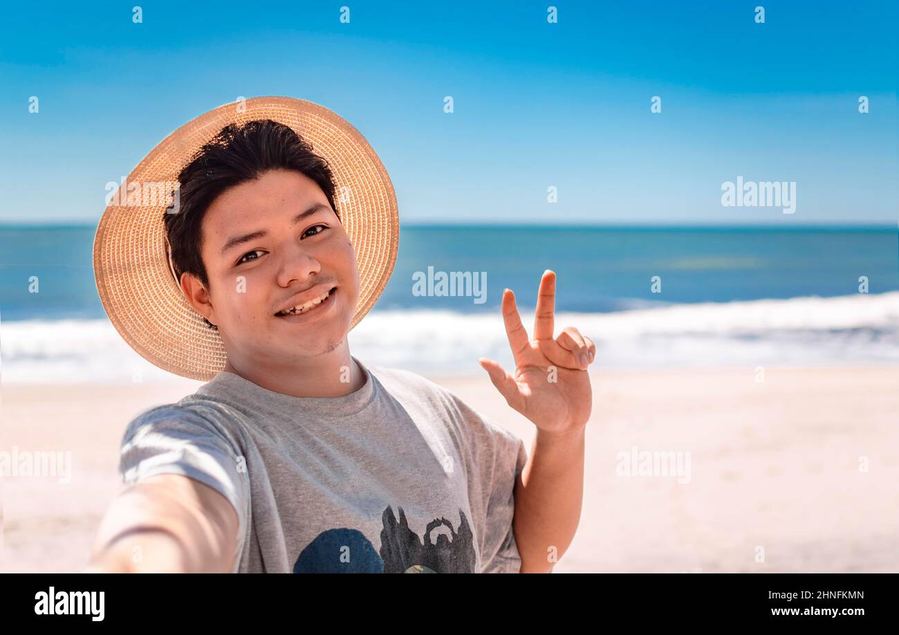 Young man taking a selfie portrait on the beach, handsome man taking a ...