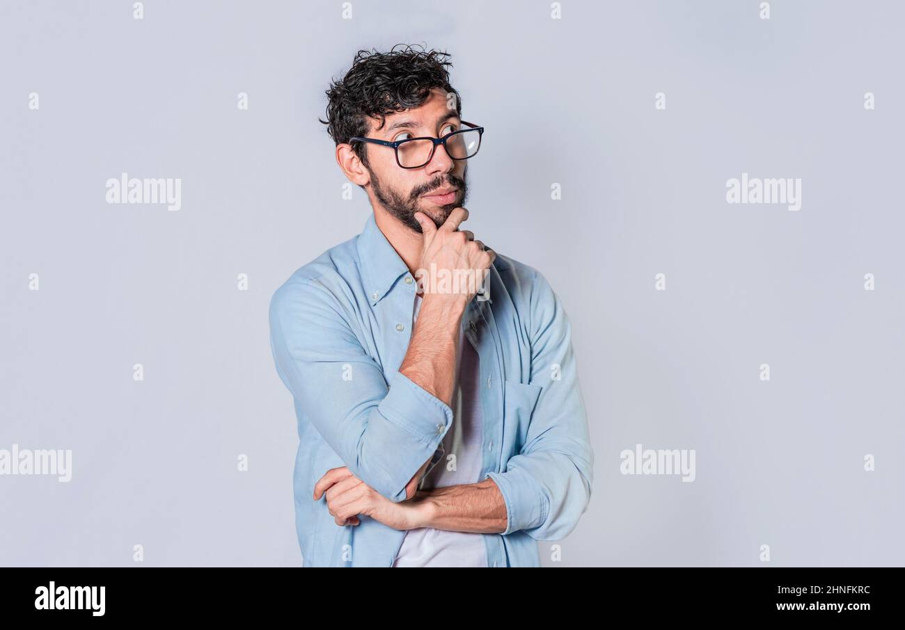 Young man wondering with his hand on his chin on an isolated background ...