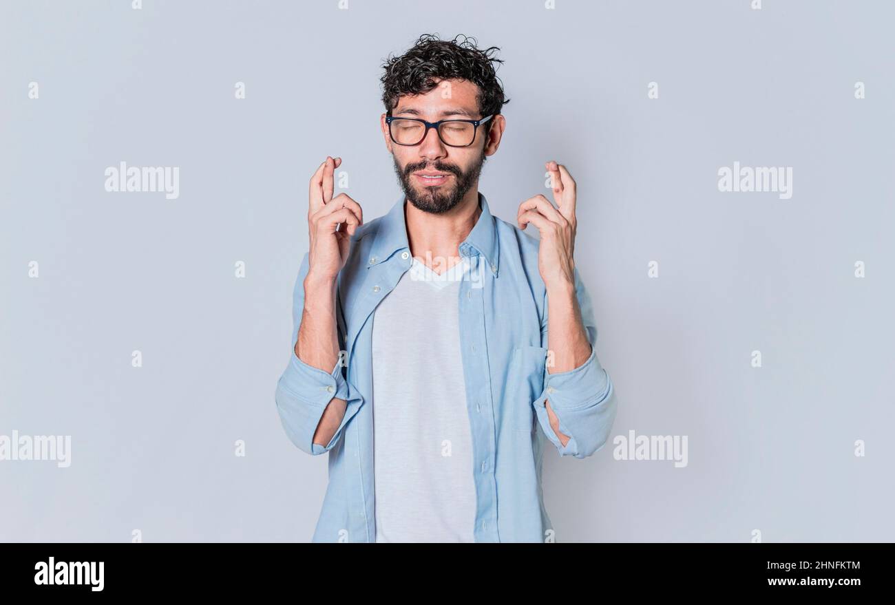 Happy man making a wish, latin guy crossing his fingers making a wish ...