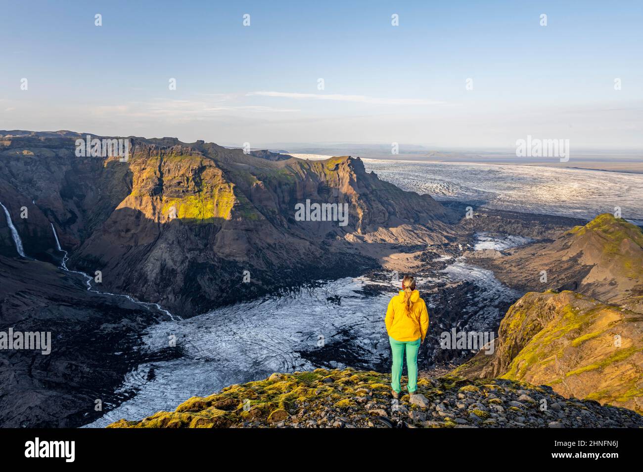 Hiker looks over spectacular landscape, cliffs and glacier ...