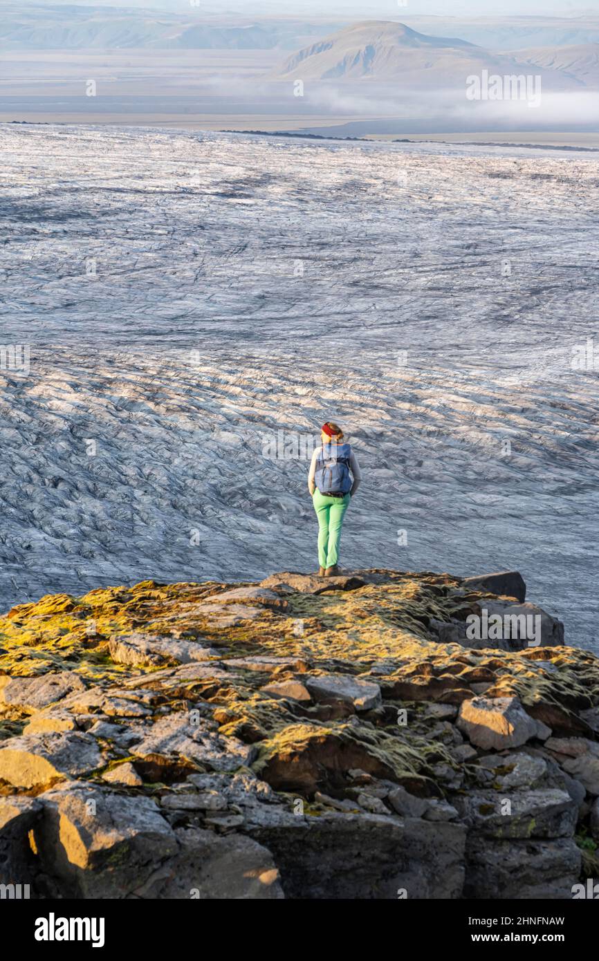Hiker looks over spectacular landscape, cliffs and glacier ...