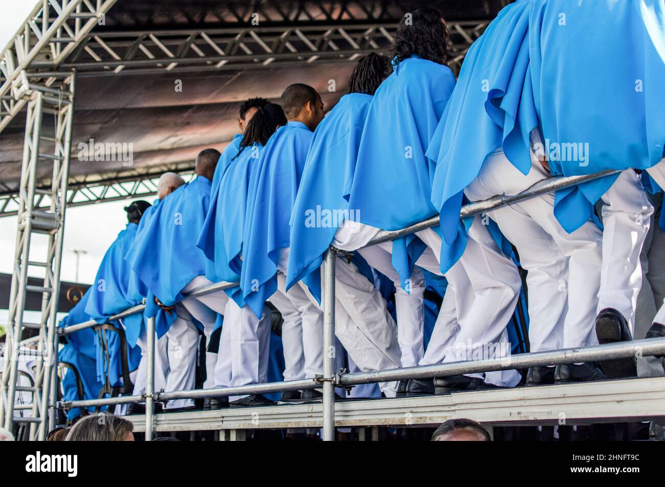 People sitting on an iron railing wearing blue and white clothing ...