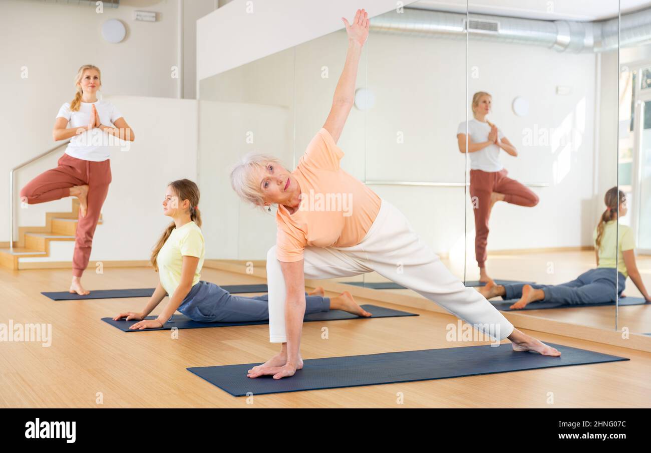 Women exercising yoga poses in fitness gym. Extended triangle pose ...
