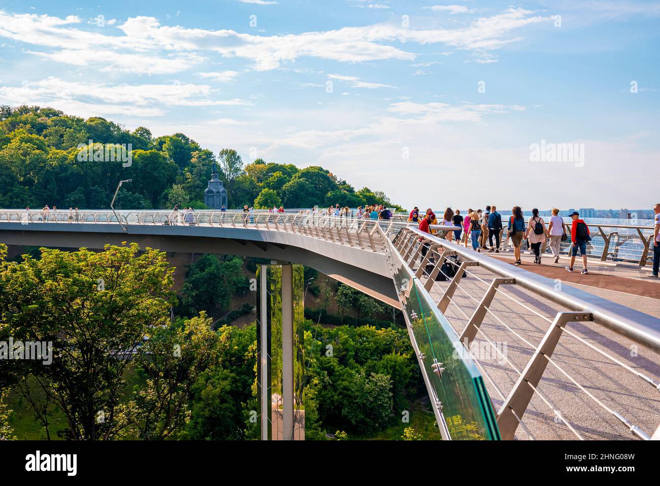 Crowd of tourists walking on pedestrian bridge with cityscape in ...