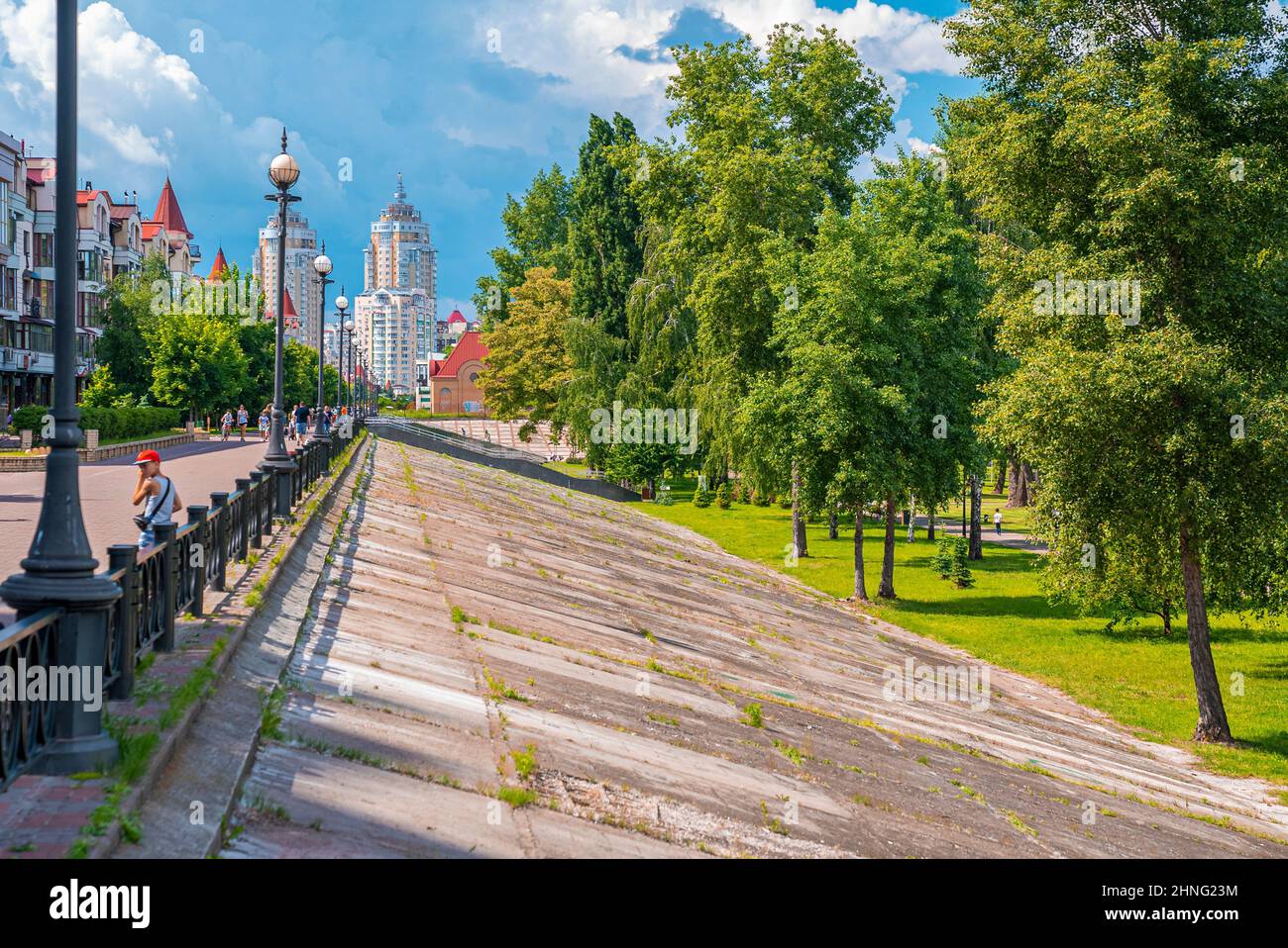 Urban green park with road against modern city buildings on sunny day ...