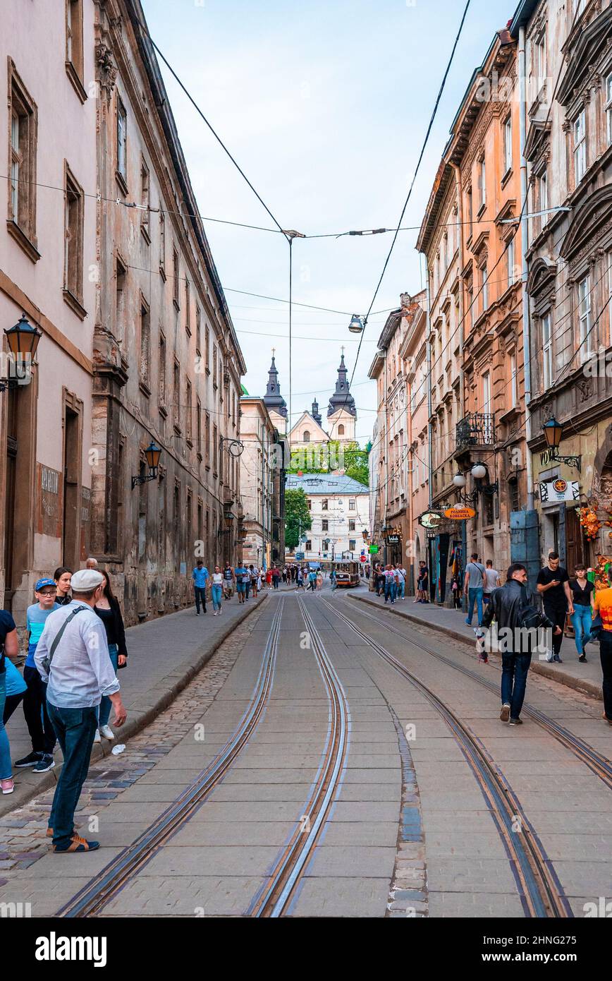 Pedestrians walking beside the tram tracks between buildings Stock ...