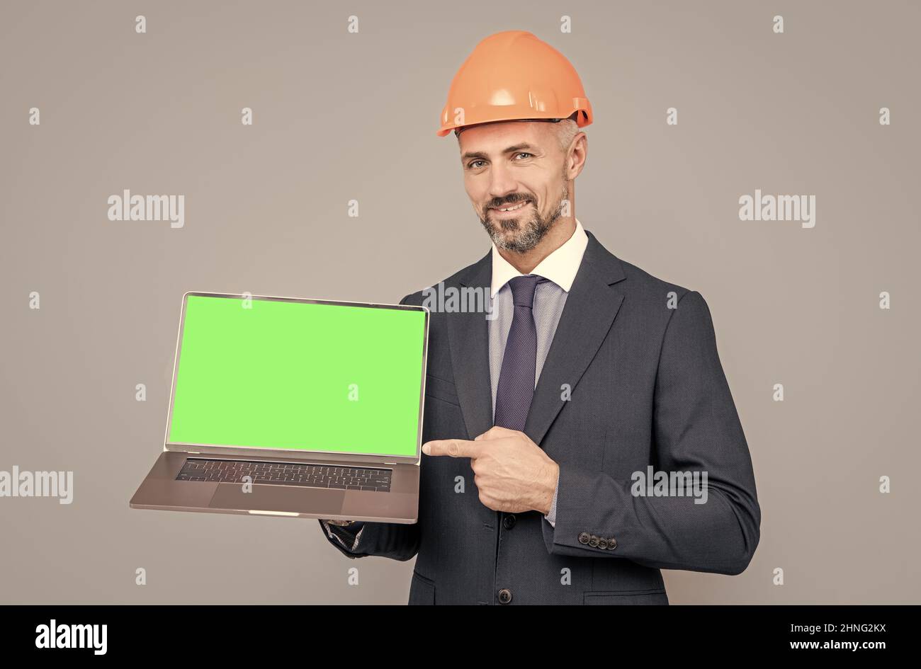 happy man in hard hat pointing finger on laptop green screen for copy ...