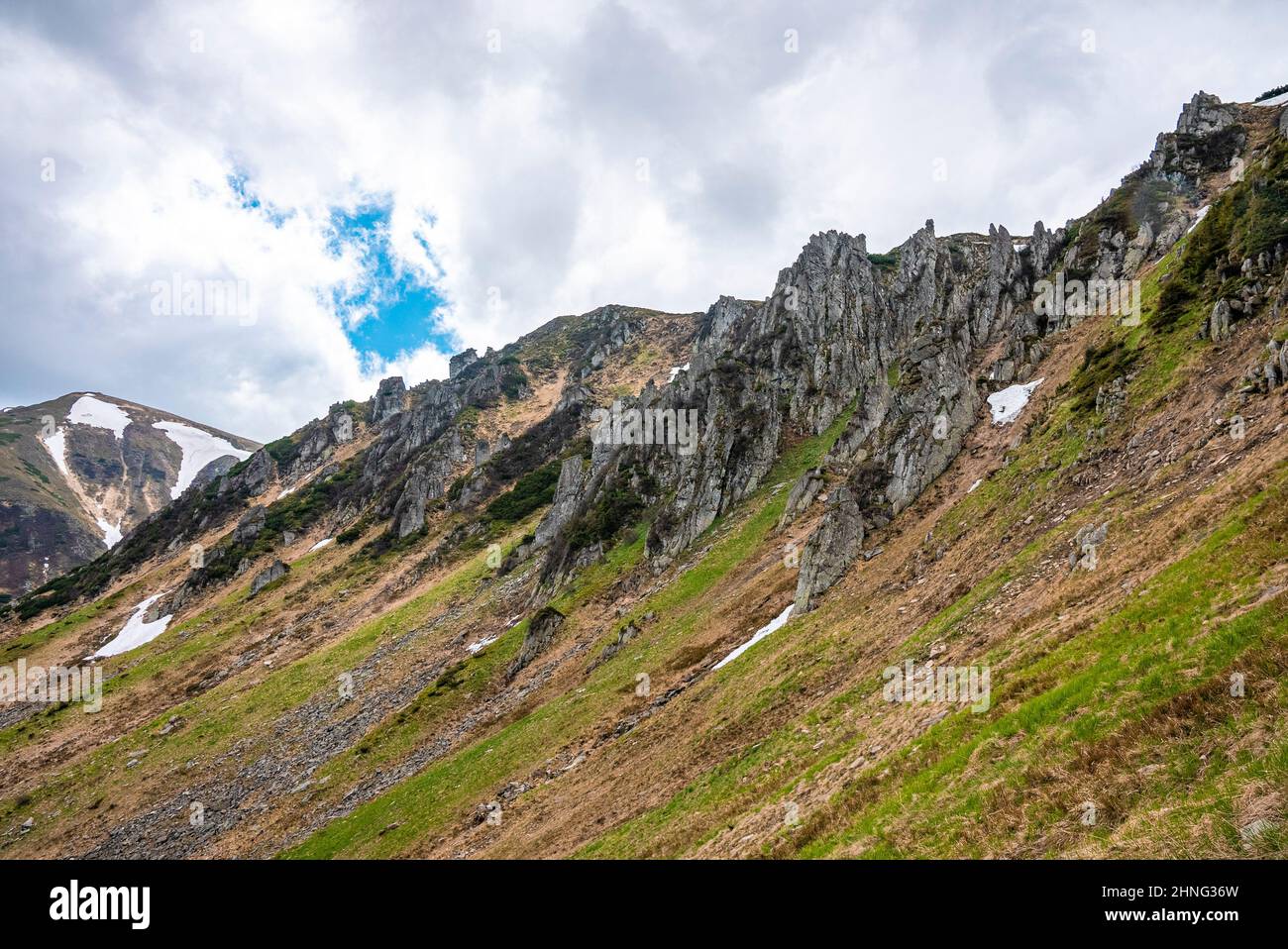 Rock cliff covered with moss over steep slope and hill against cloudy ...
