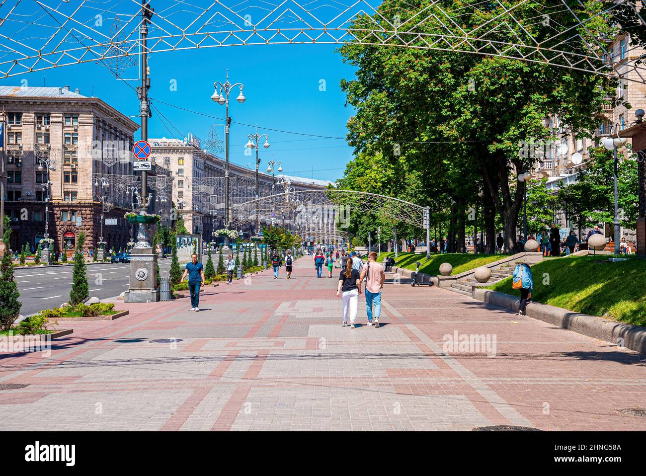 People walking on roadside footpath under arched framework in urban ...