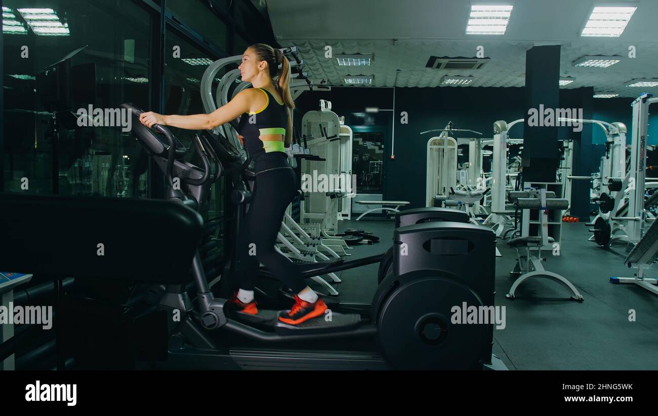 Fit Athletic Woman Exercising on an Elliptical Machine. Muscular Women ...