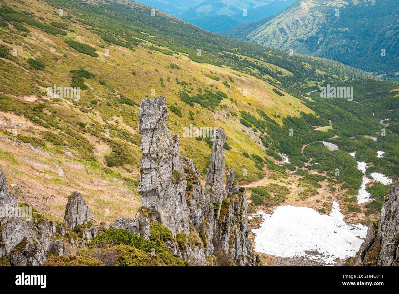 Rock cliff covered with moss and snow against slope of mountain Stock ...