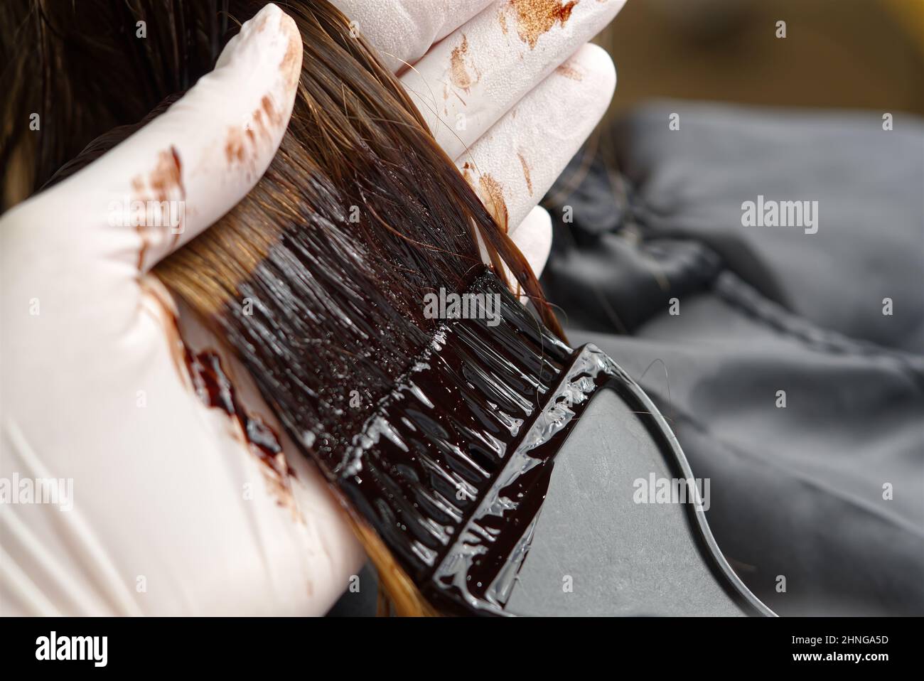 Young female hairdressed hands dyeing long hair to beautiful girl ...