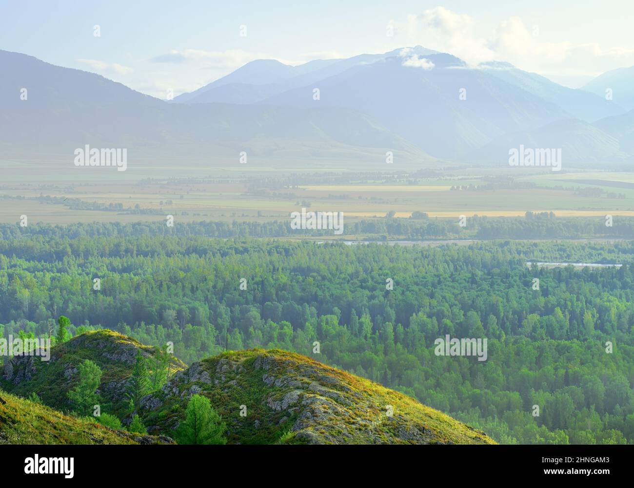 A green mountain slope above a mountain plain under a blue sky ...