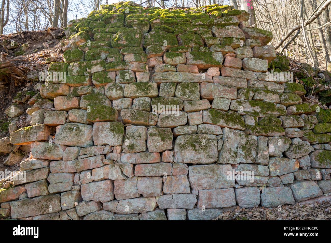 Ancient fragments of rock wall in the forest protecting road from ...