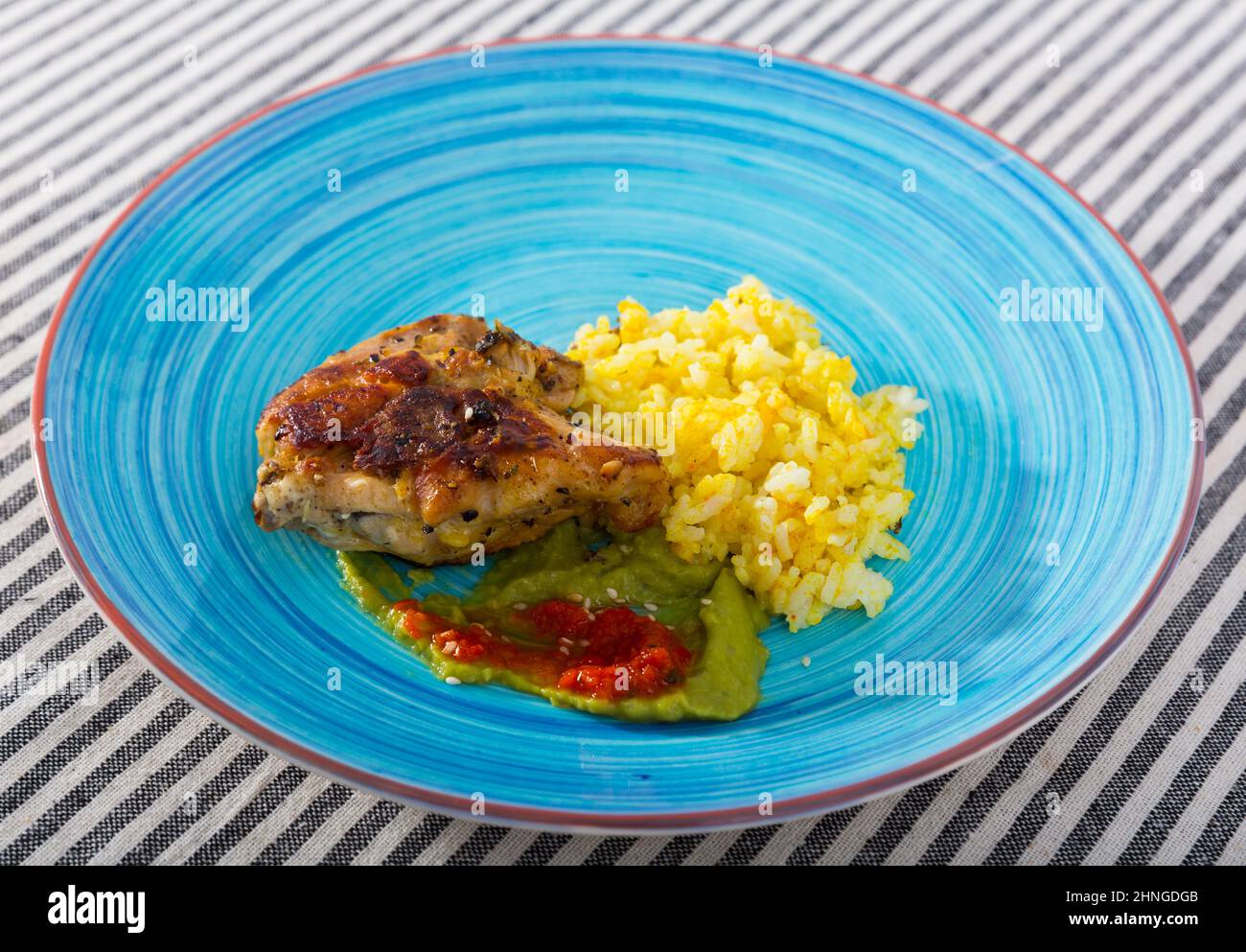 Fried chicken thighs with yellow rice and sauces Stock Photo - Alamy