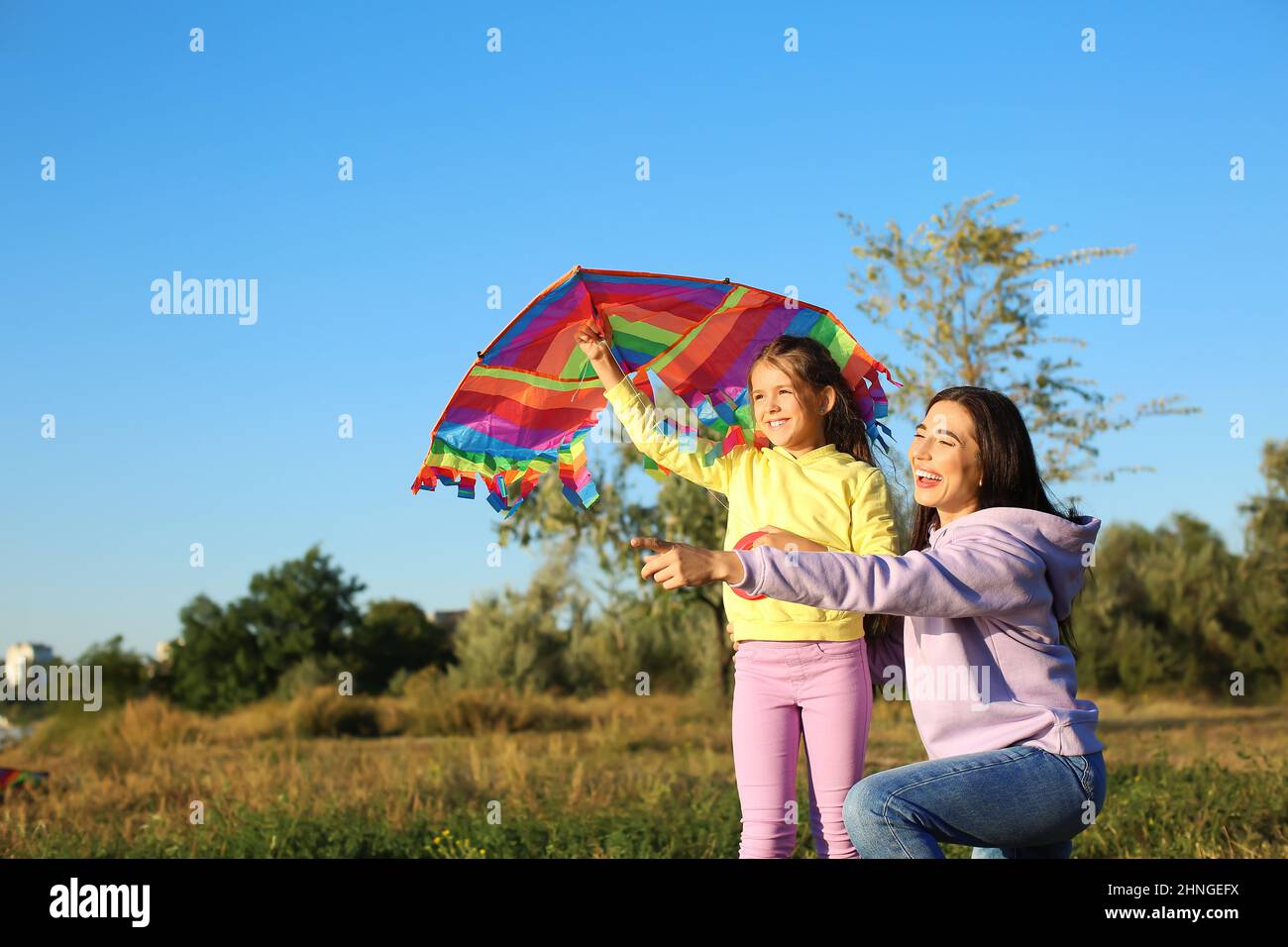 Cute little girl with kite and her mother pointing at something ...