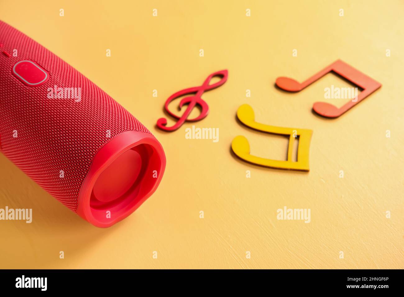 Wireless portable speaker and music notes on color background, closeup ...