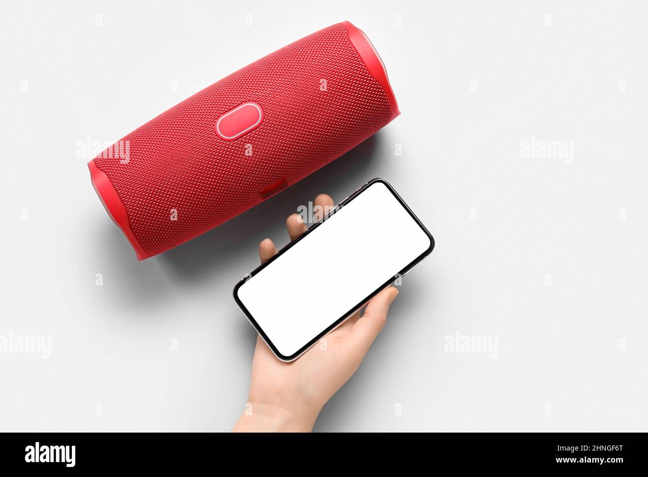 Female hand with mobile phone and wireless portable speaker on light ...