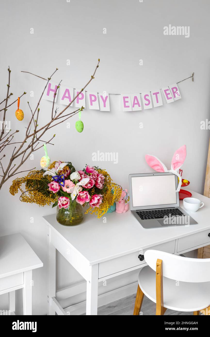 Workplace with modern laptop and stylish decor for Easter celebration ...