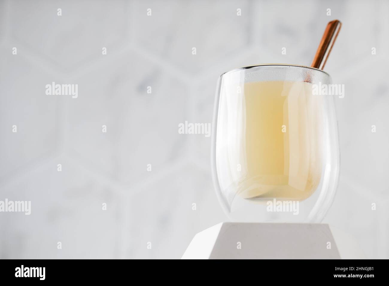 Healthy bone broth in a transparent mug on a pedestal with a spoon on a ...